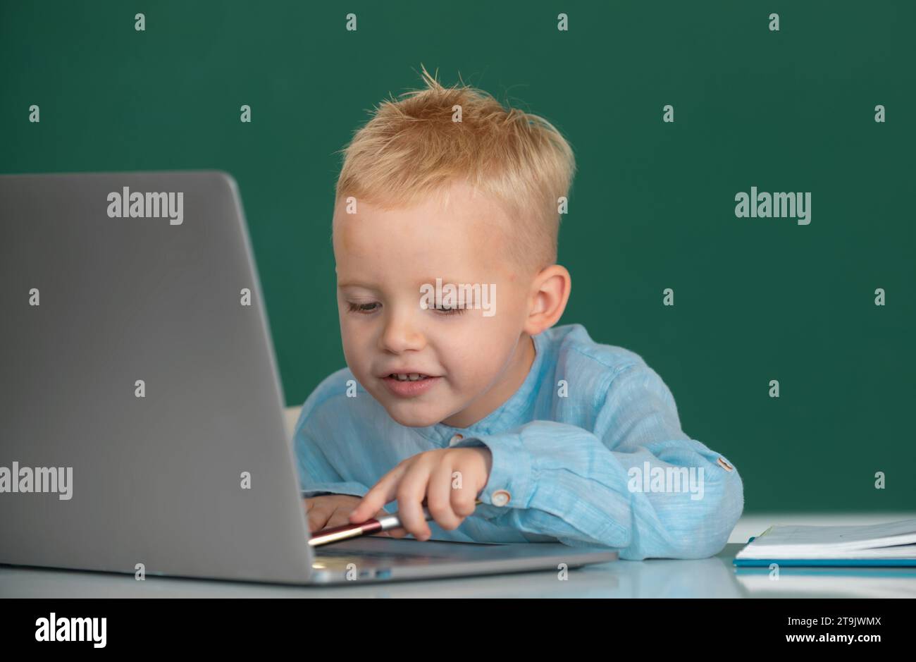 Elementary school kid working in computer class. Funny blonde pupil on ...