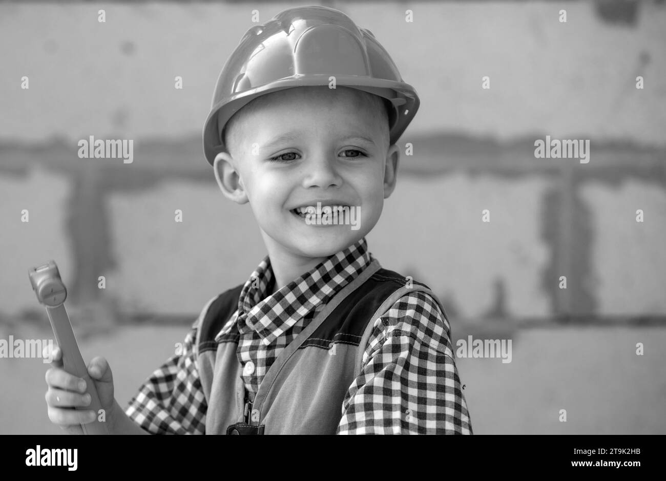 Kid in hard hat holding hammer. Happy smiling little child helping with ...