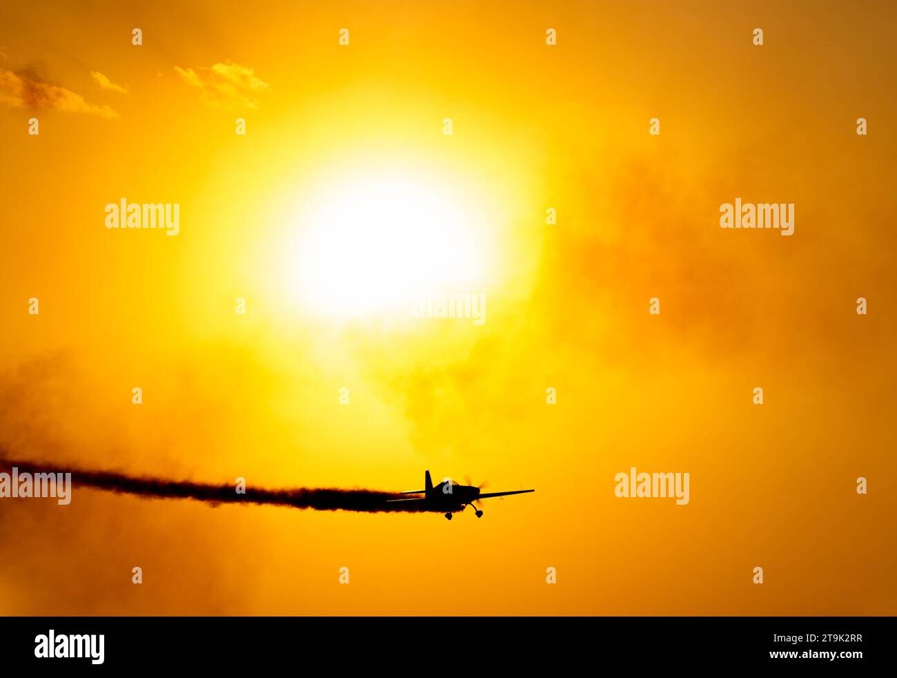 A silhouette of an aerobatic airplane flying at sunset against the ...