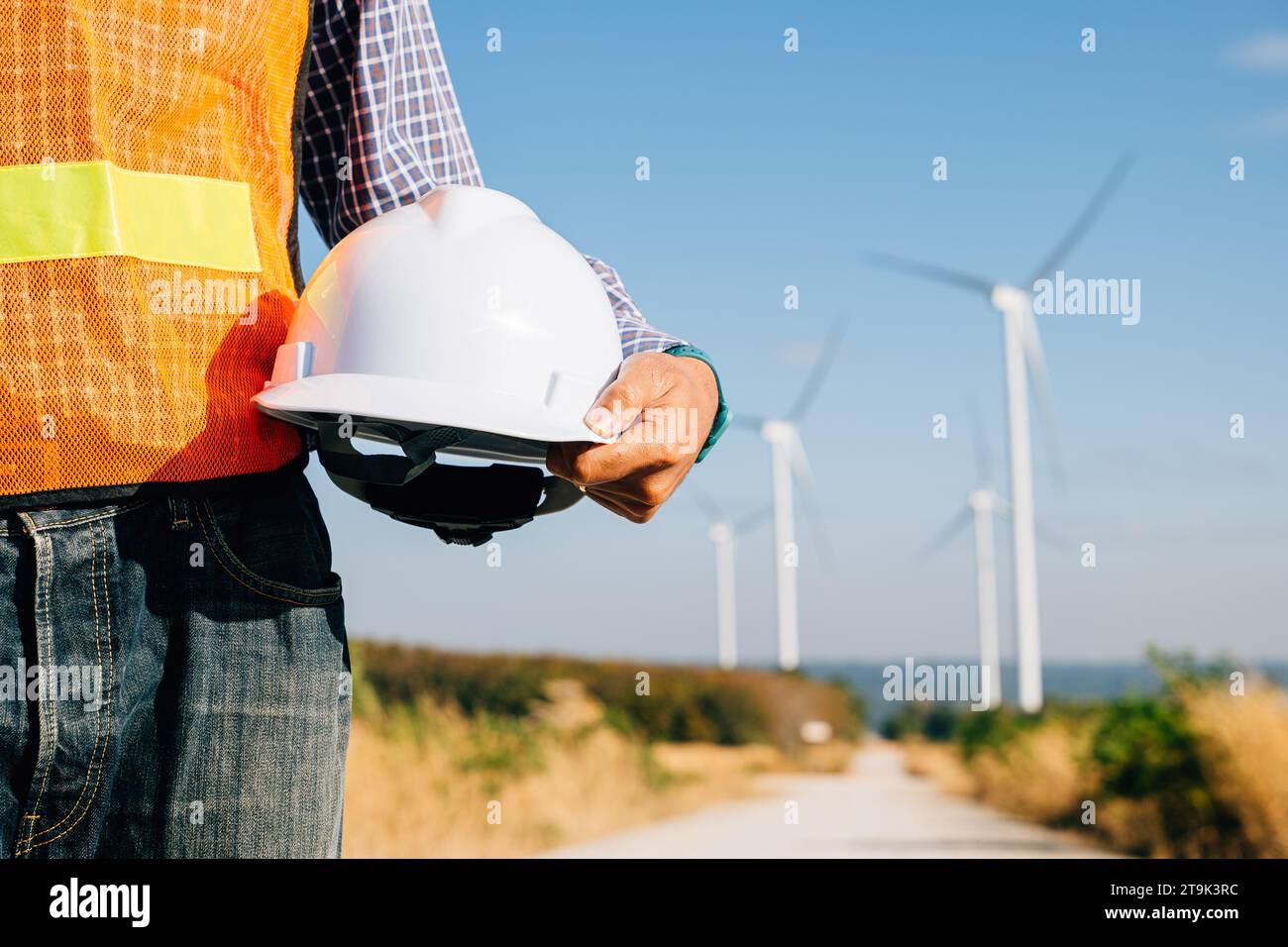 Engineer holding safety helmet stands at windmill field Stock Photo - Alamy