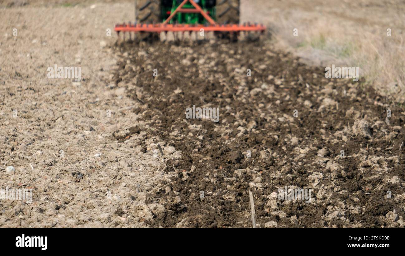Close-up of agriculture tractor cultivating seeding plough field farm ...