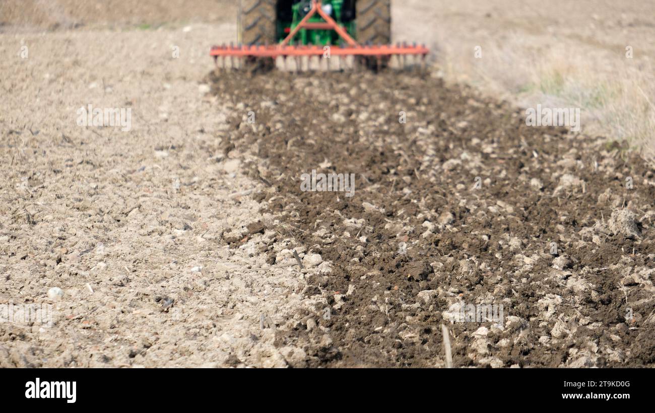 Close-up of agriculture tractor cultivating seeding plough field farm ...