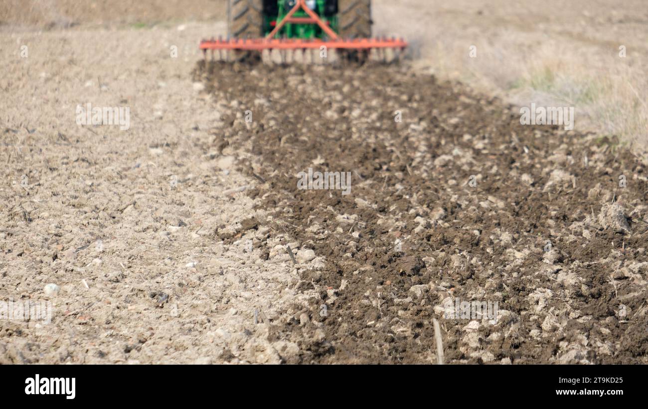 Close-up of agriculture tractor cultivating seeding plough field farm ...