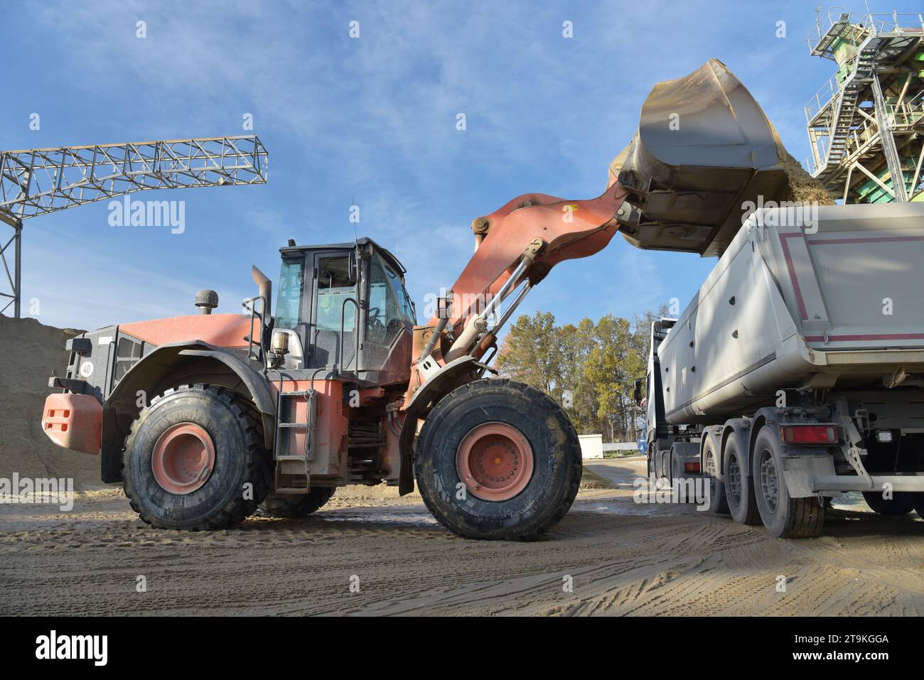 Wheel loader loads truck with gravel in a sand pit - transport and ...