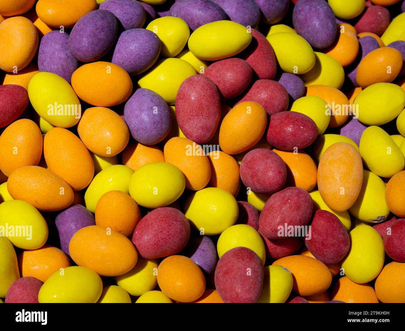 A close-up of a pile of colorful candy-coated chocolates in purple ...