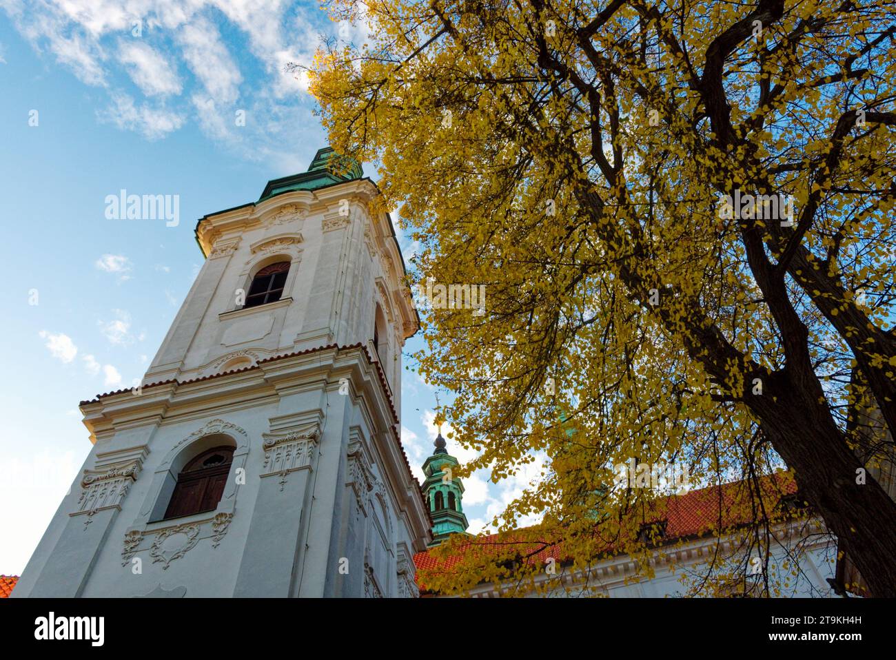 A white church with a green dome and spire, surrounded by yellow-leaved ...