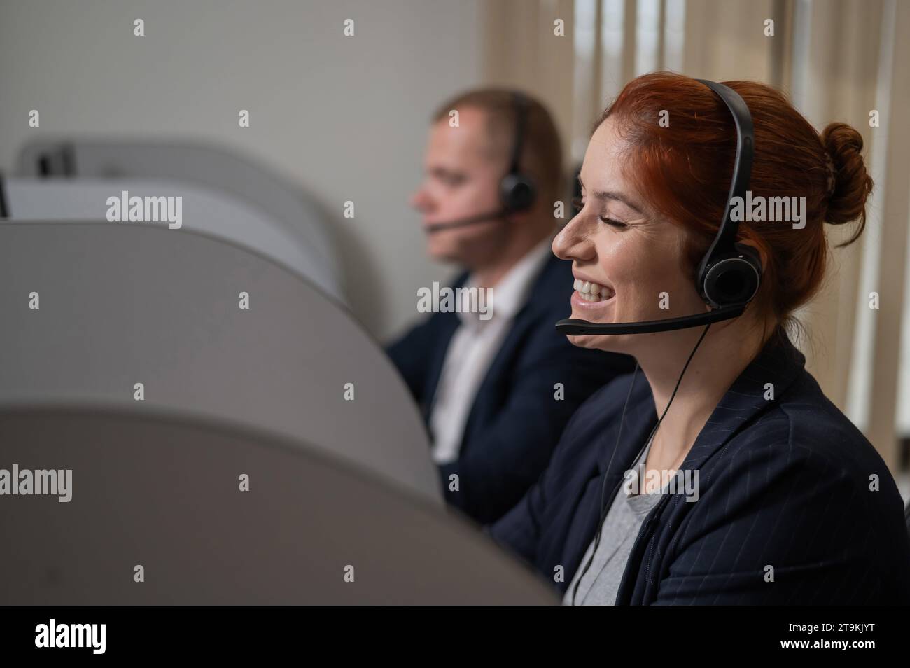 Two friendly call center employees talking to customers. Man and woman working with headsets in ...