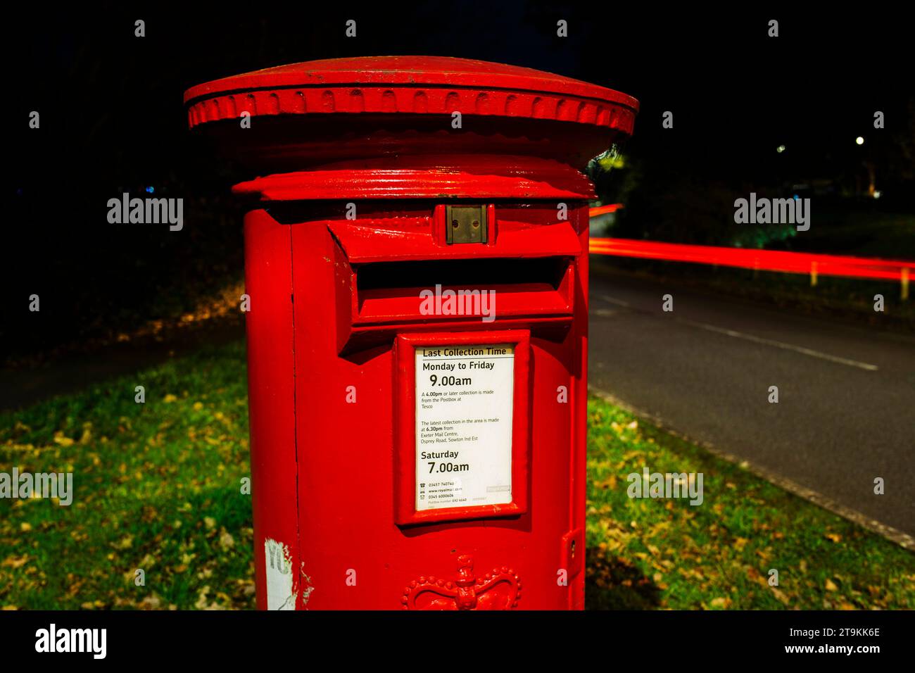 red letter box standing in front of road with long exposure of car ...