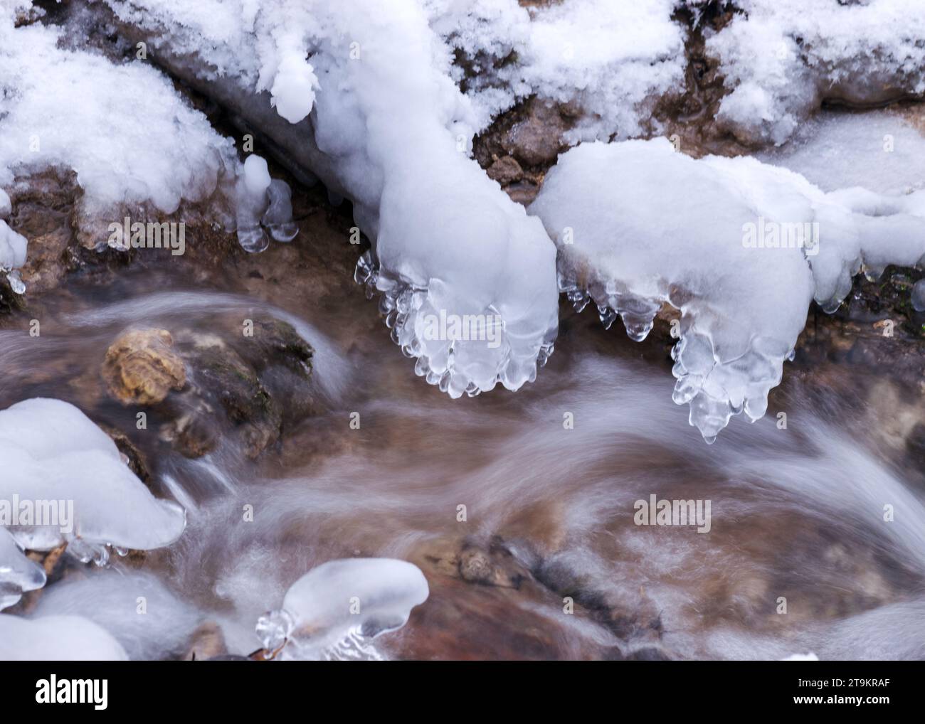 frozen fast flowing spring water, icy rocks and water stream, frosty ...