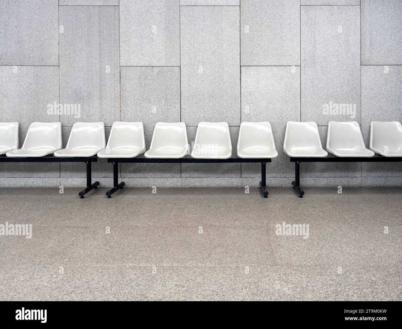 Scene of row of empty waiting chair set with white plastic seats with ...