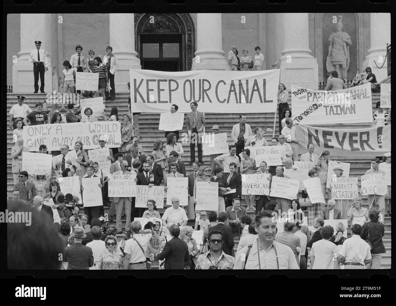 Crowd with signs and banners, arranged on steps of unidentified ...