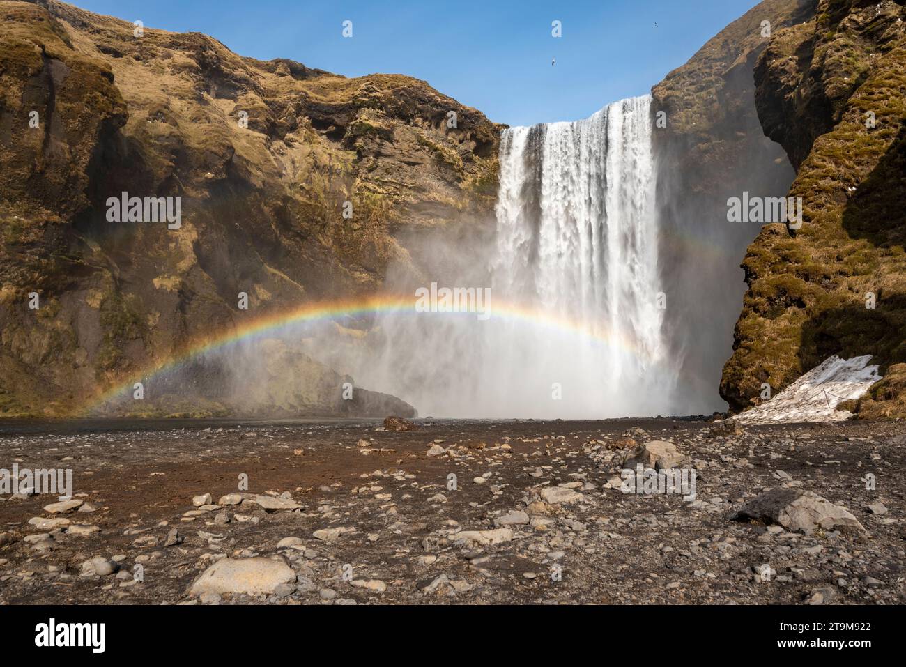 The famous Skógafoss waterfall under a clear blue sky, with a beautiful ...