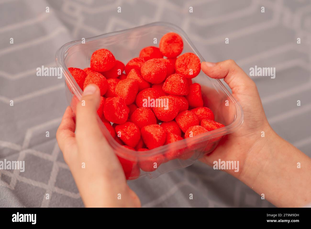 Sugar-coated joy: child's hands excitedly reaching for red fruity ...