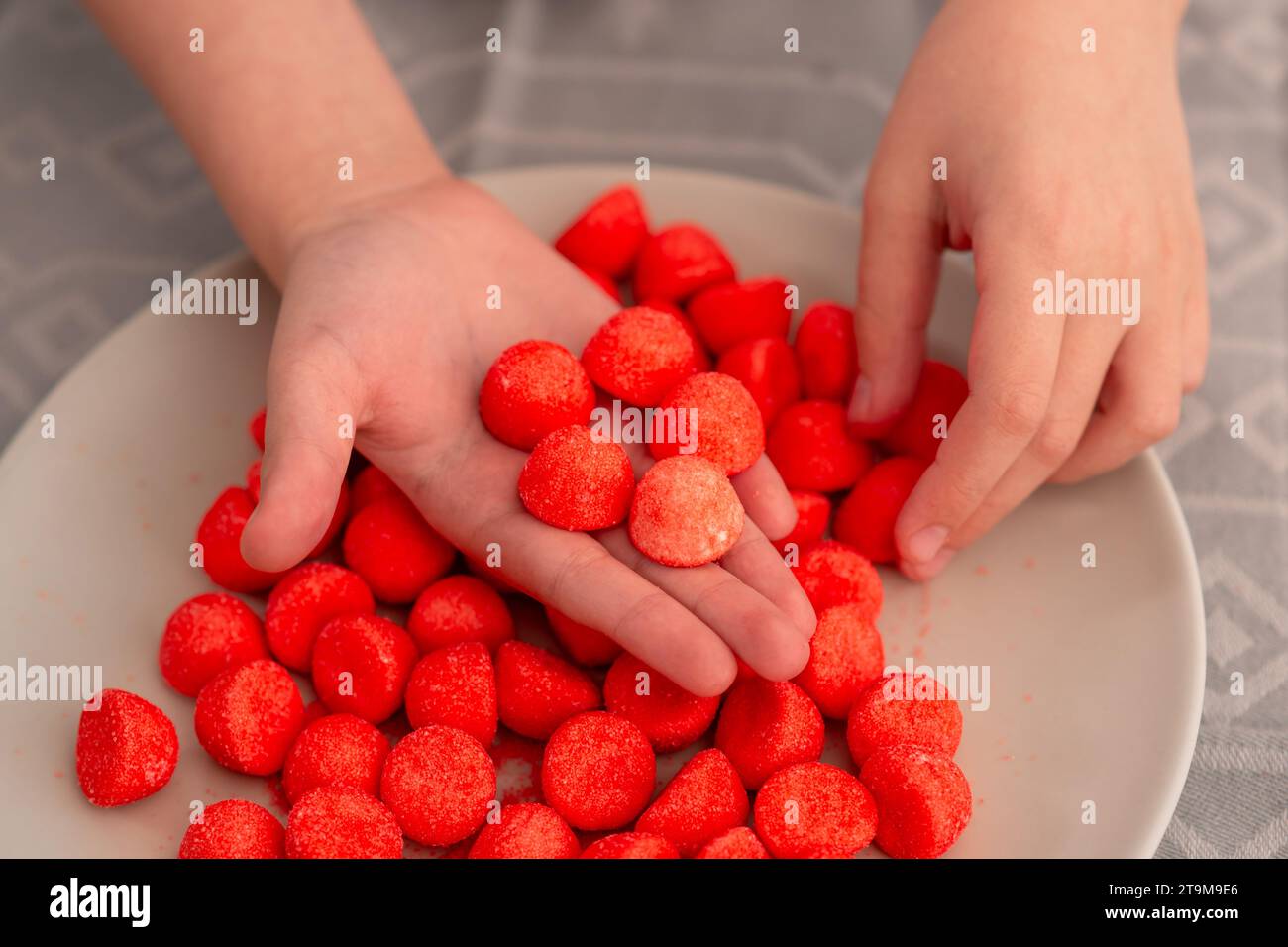 Red fruity confections beckon as a child's hands reach for them on a ...