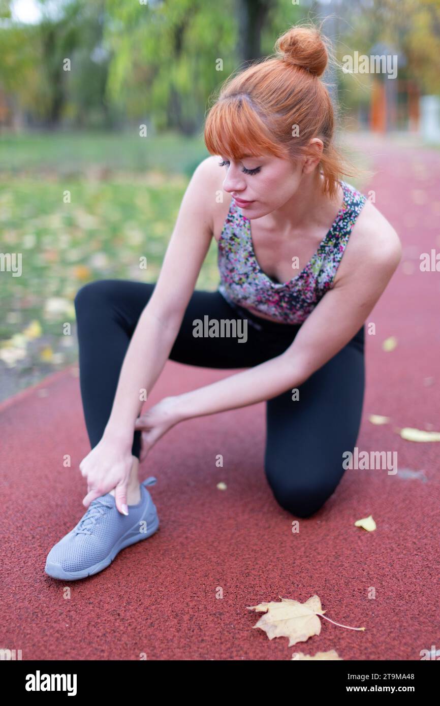 Young redhaed Caucasian woman in sportswear with ankle injury on ...
