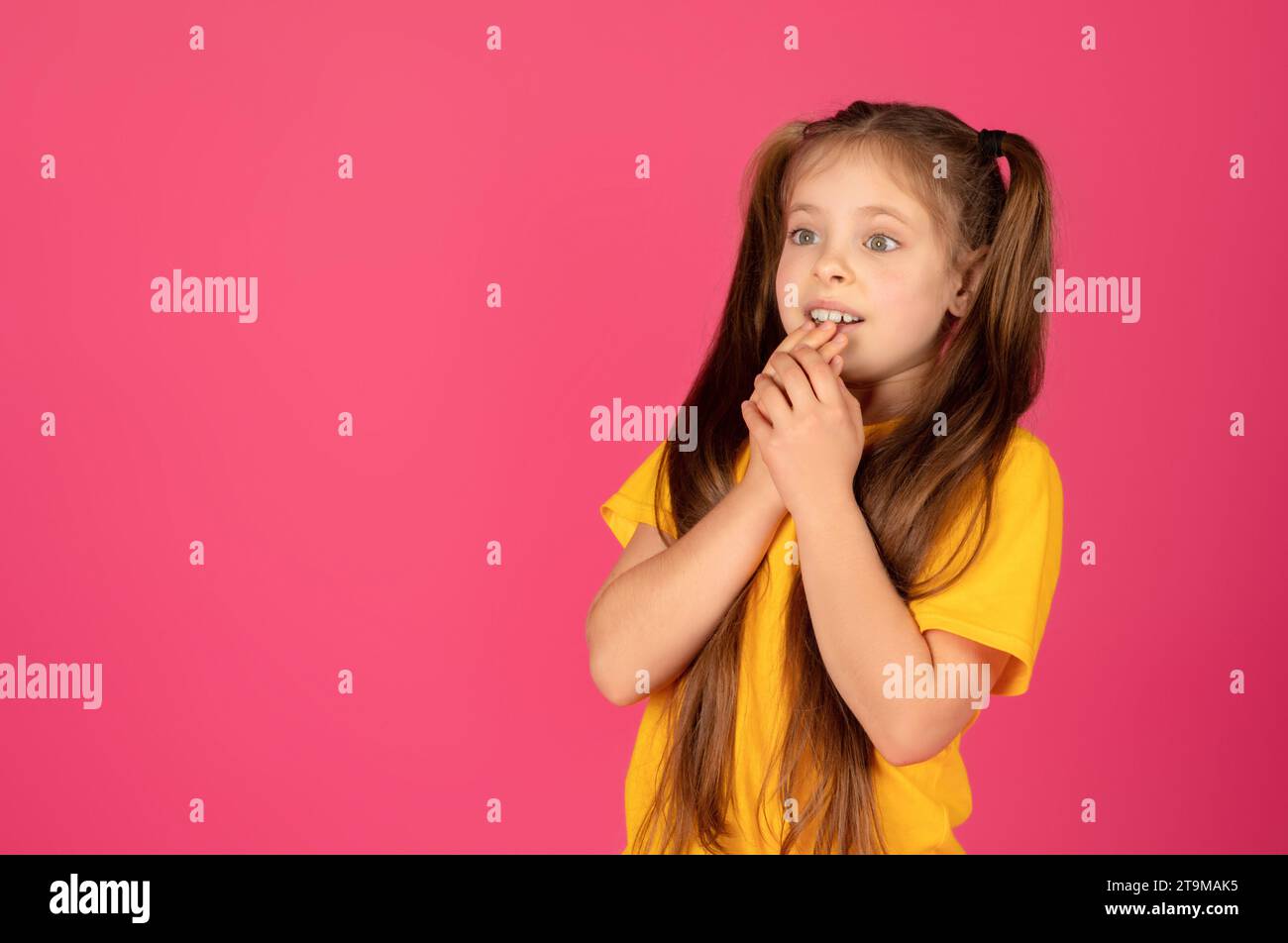 Pensive young girl looking at copy space with excitement and biting ...