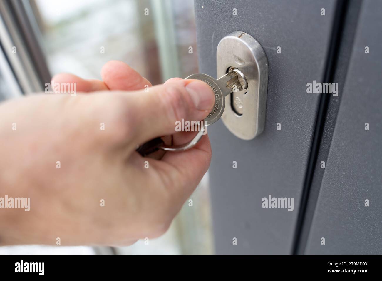 Bavaria, Germany - November 26, 2023: A man unlocks a door with a key ...
