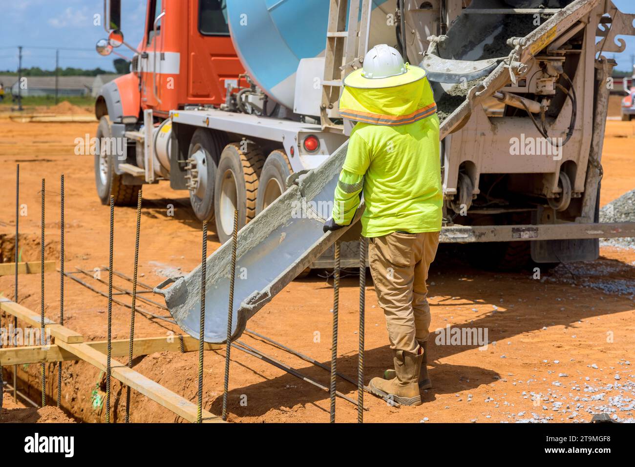 Construction worker laying cement pouring concrete in trenches for ...