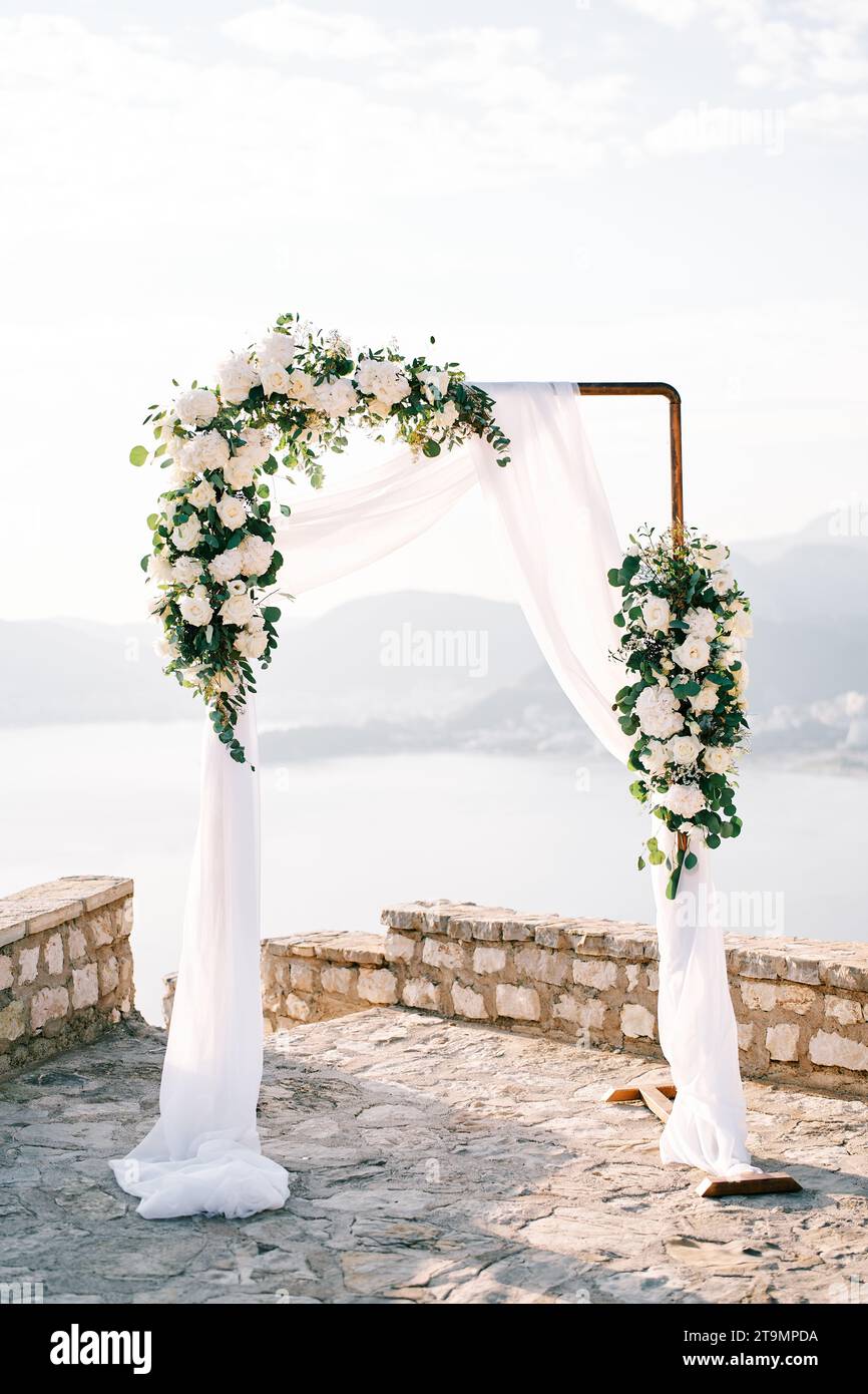 Rectangular wedding arch decorated with white fabric stands on an ...