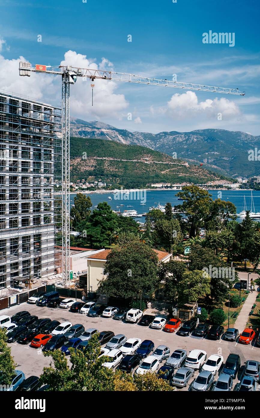 Parking lot with cars in front of a tall building under construction in ...