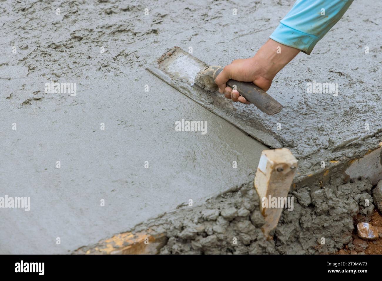 Mason leveling fresh concrete pavement with wet cement using special ...