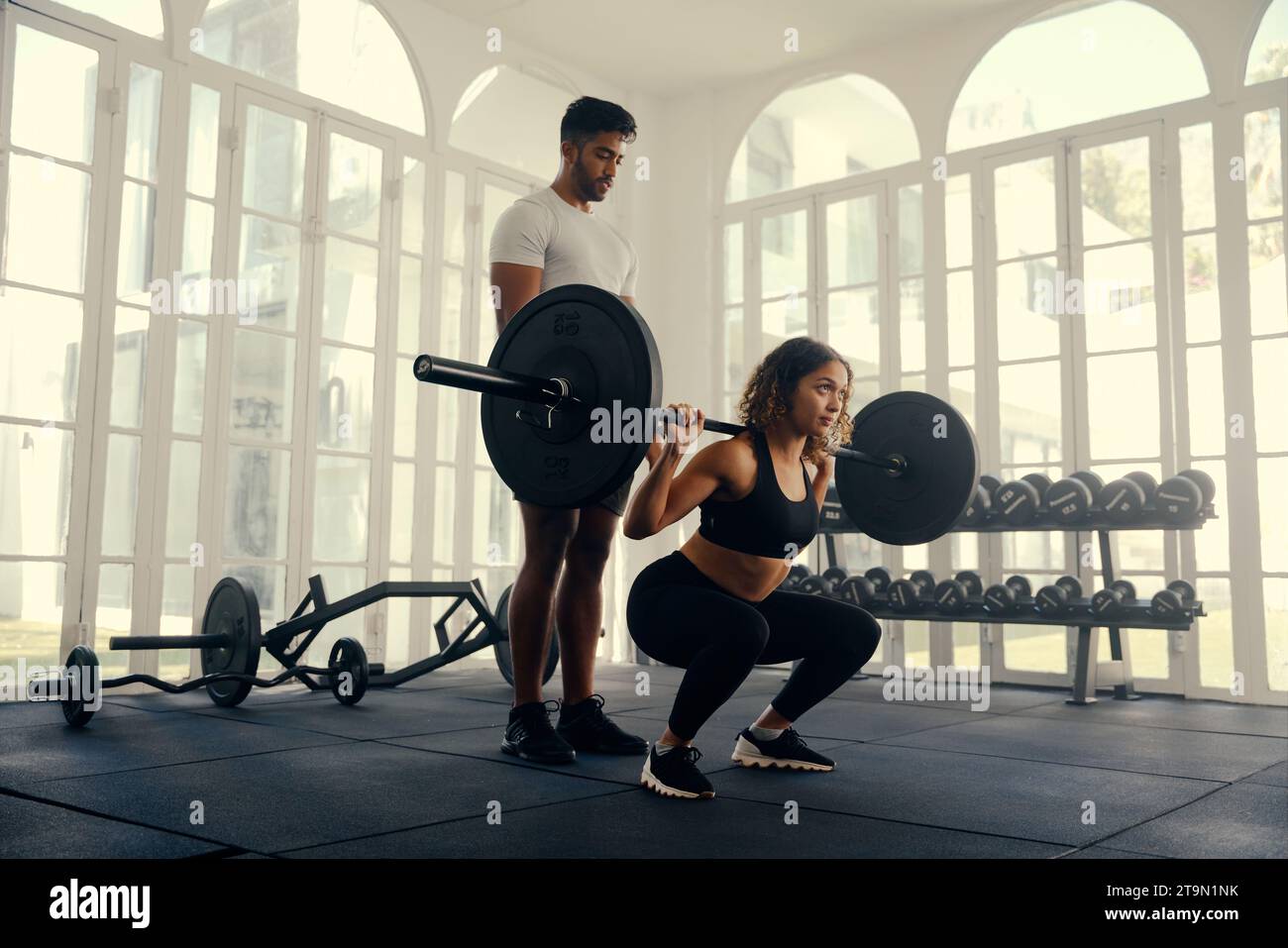 Two fit multiracial young adults in sports clothing doing weight ...