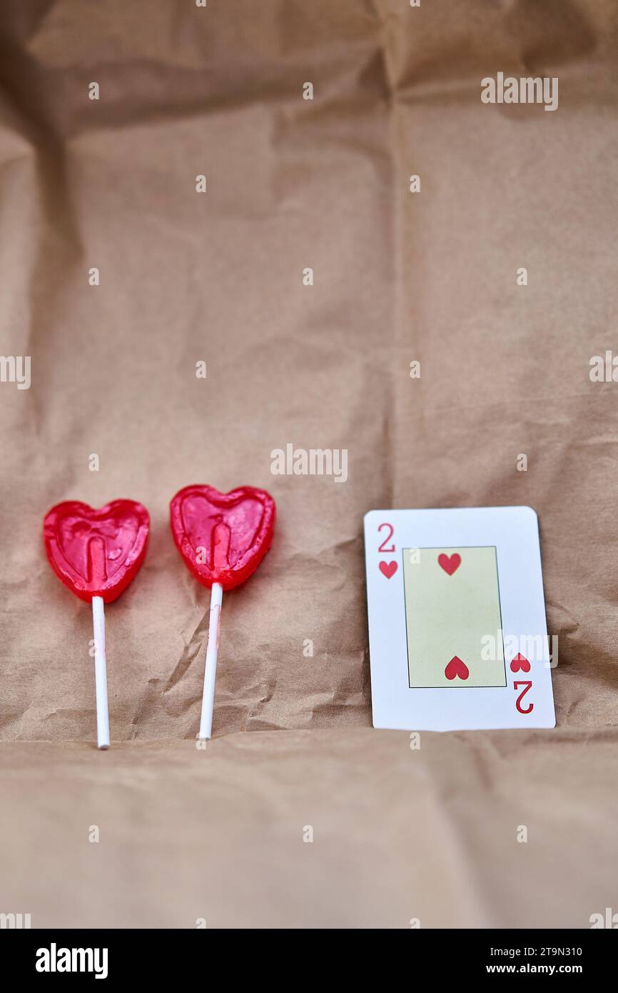 Two red heart-shaped lollipops and a two hearts card on a cardboard ...