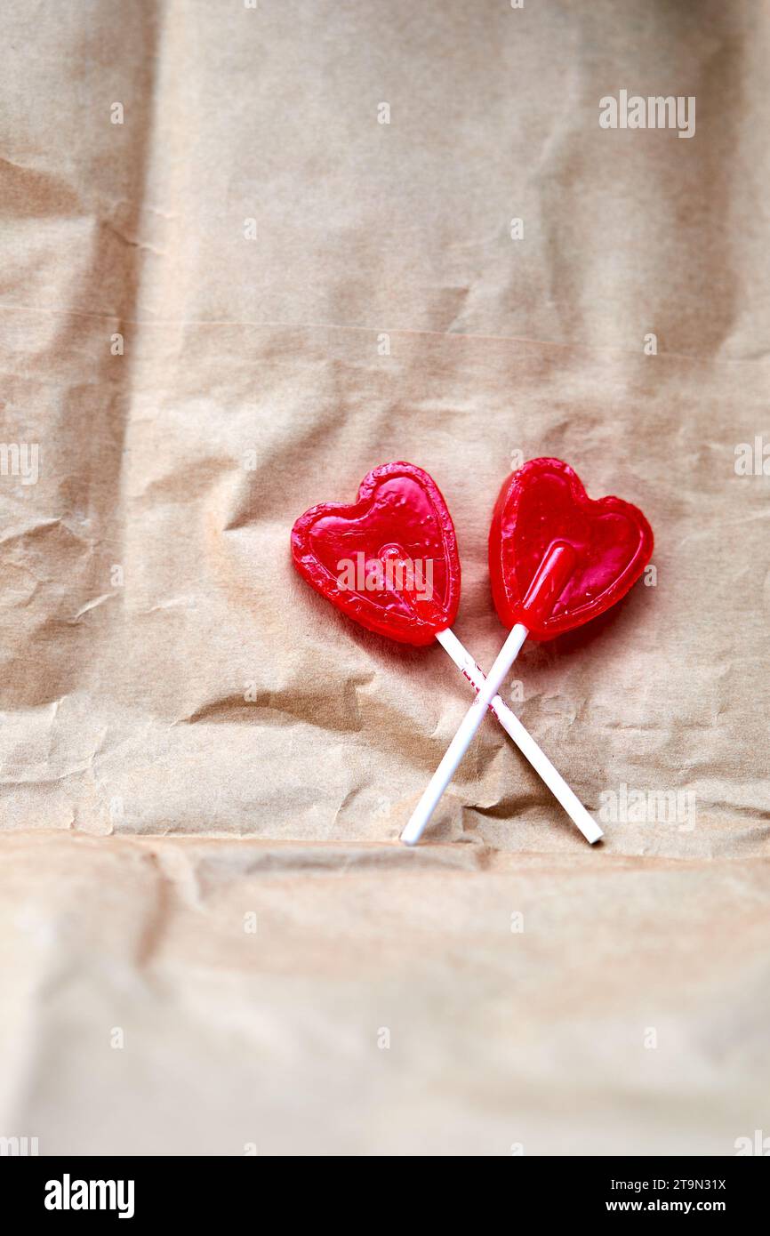 Two red heart-shaped lollipops together on a cardboard background Stock ...