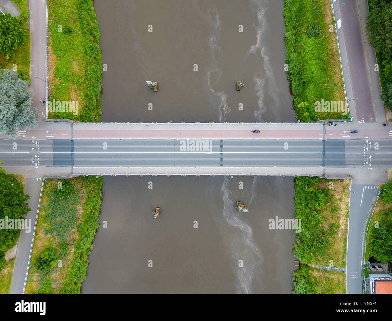 This image offers an aerial view of a bridge spanning a flowing body of ...