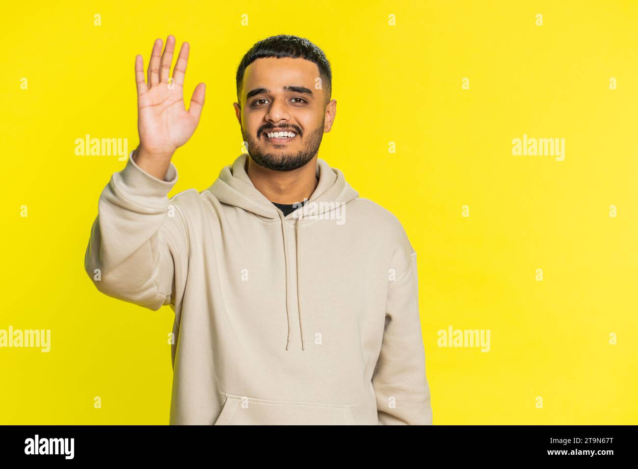 Lovely Indian man smiling friendly at camera, waving hands gesturing ...