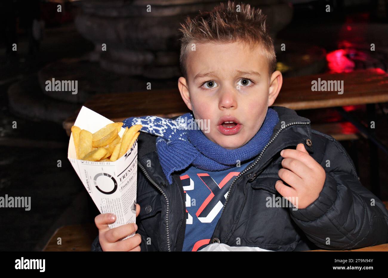 Night image, portrait of a blond boy with a cone of French fries Stock ...