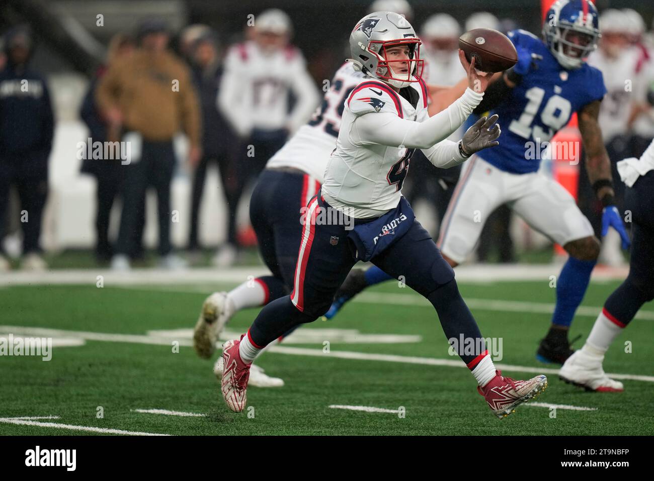 New England Patriots quarterback Bailey Zappe (4) shoves a lateral pass ...