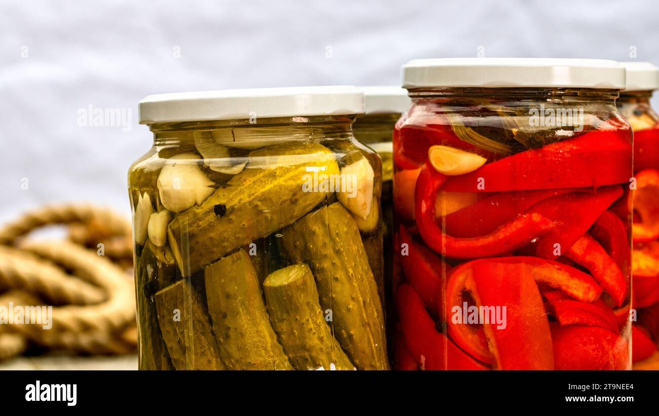 Glass jars with pickled red bell peppers and pickled cucumbers (pickles) isolated. Jars with ...