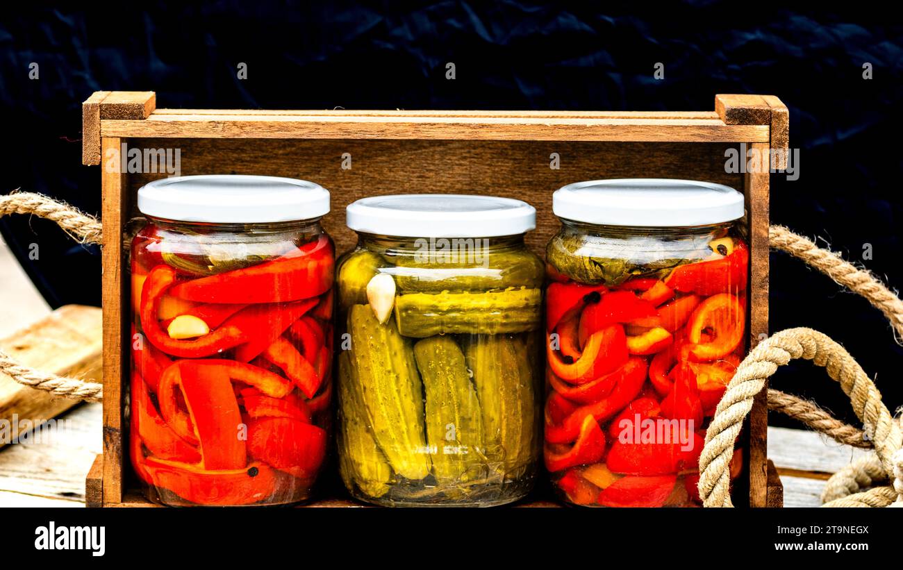 Wooden crate with glass jars with pickled red bell peppers and pickled ...