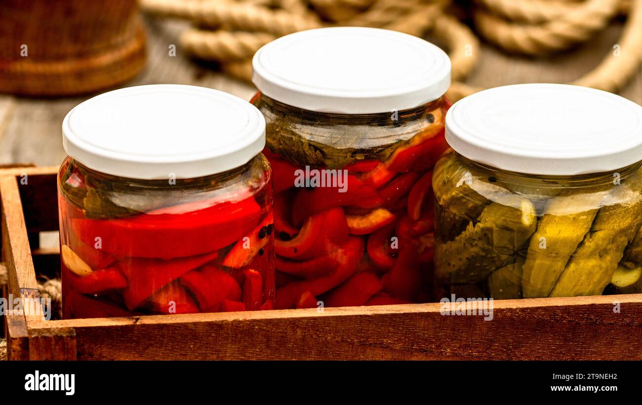 Wooden crate with glass jars with pickled red bell peppers and pickled ...