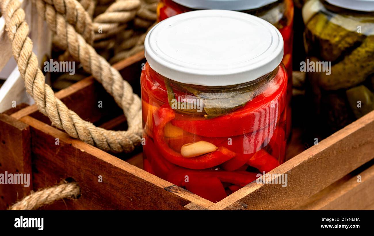 Wooden crate with glass jars with pickled red bell peppers and pickled ...