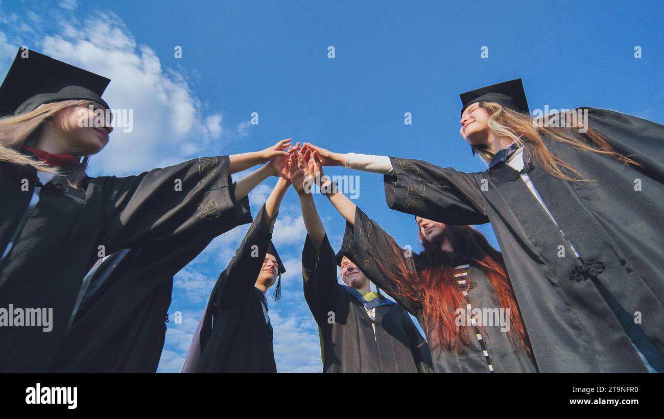 Group of happy successful graduates in academic hats and robes standing ...