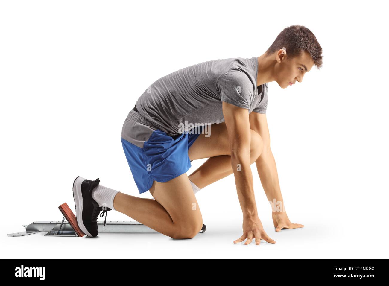 Full length profile shot of a young man kneeling on running start ...