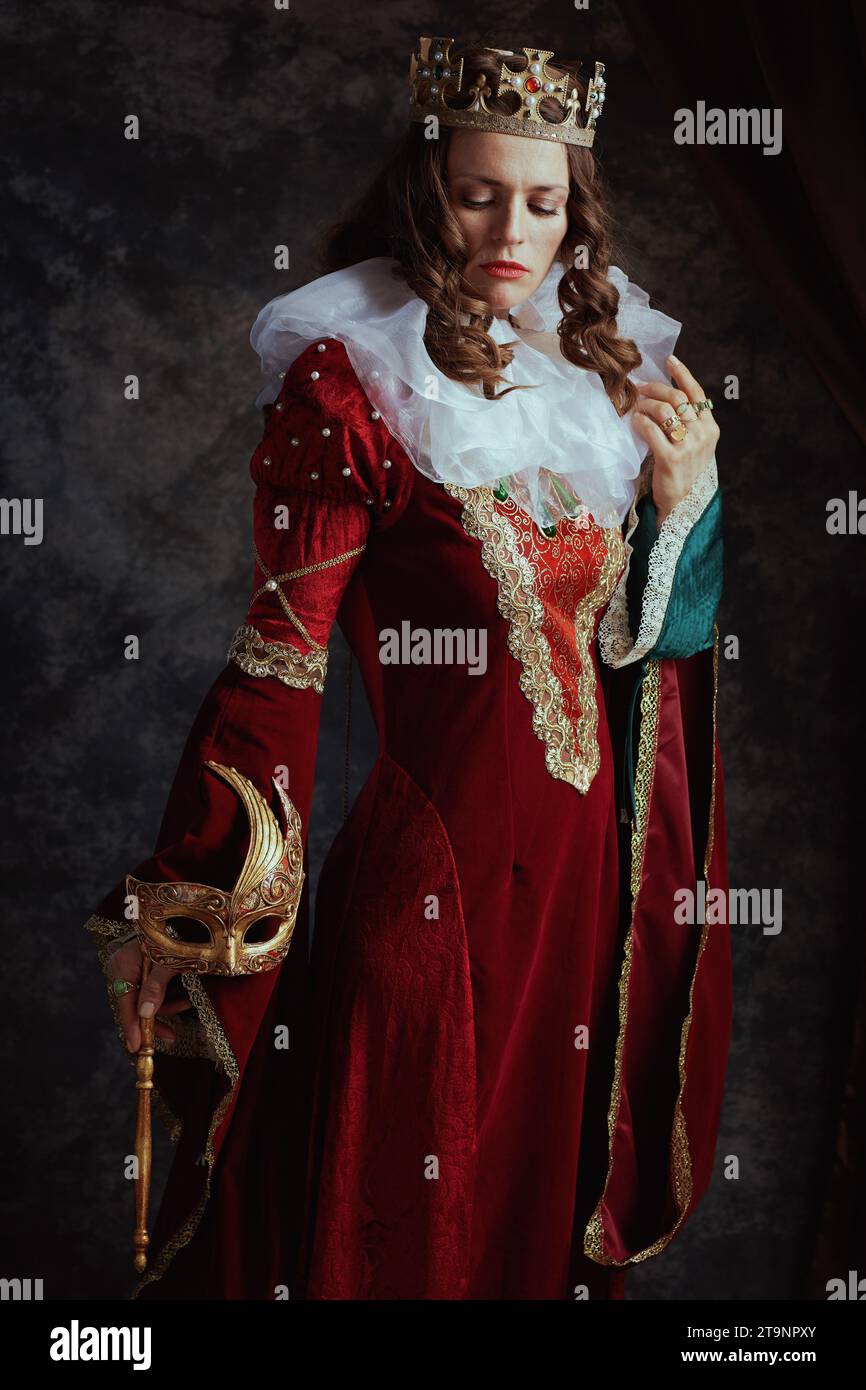 medieval queen in red dress with venetian mask, white collar and crown ...