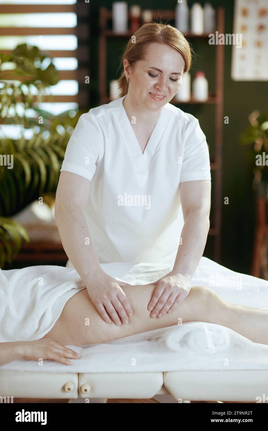 Healthcare time. medical massage therapist in spa salon massaging clients leg on massage table ...
