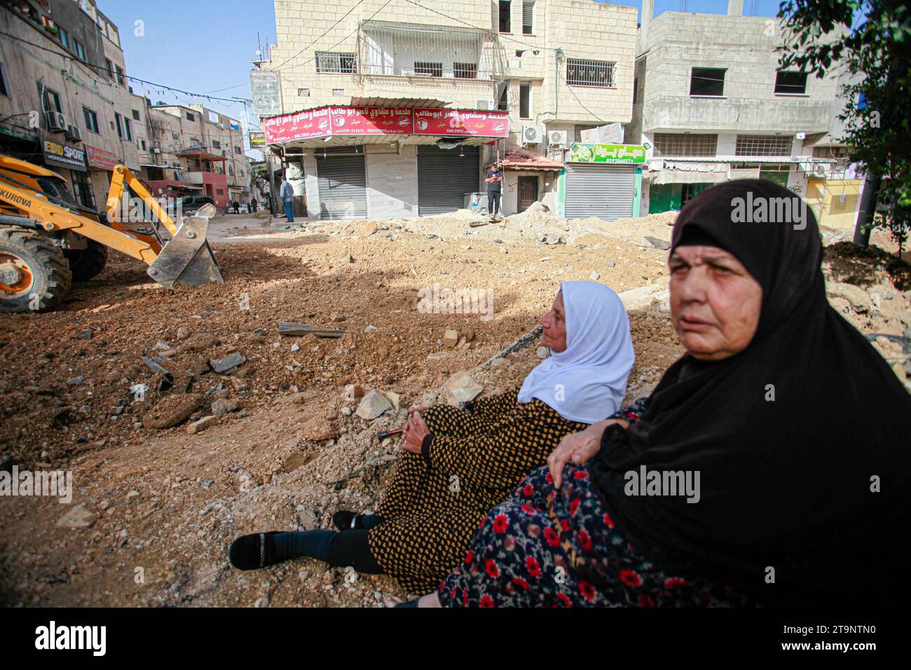 Jenin, Palestine. 26th Nov, 2023. Women sit nearby a destroyed building ...