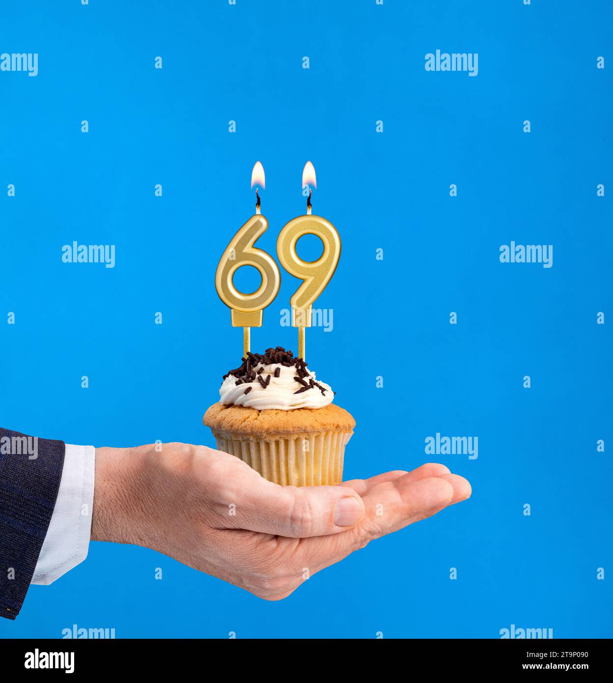 Hand holding a cupcake with the number 69 candle - Birthday on blue ...