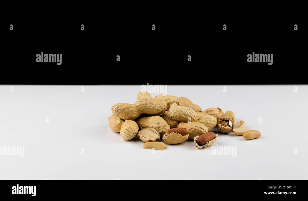 Peanuts in their shells on a white table, peeled and unshelled peanuts ...