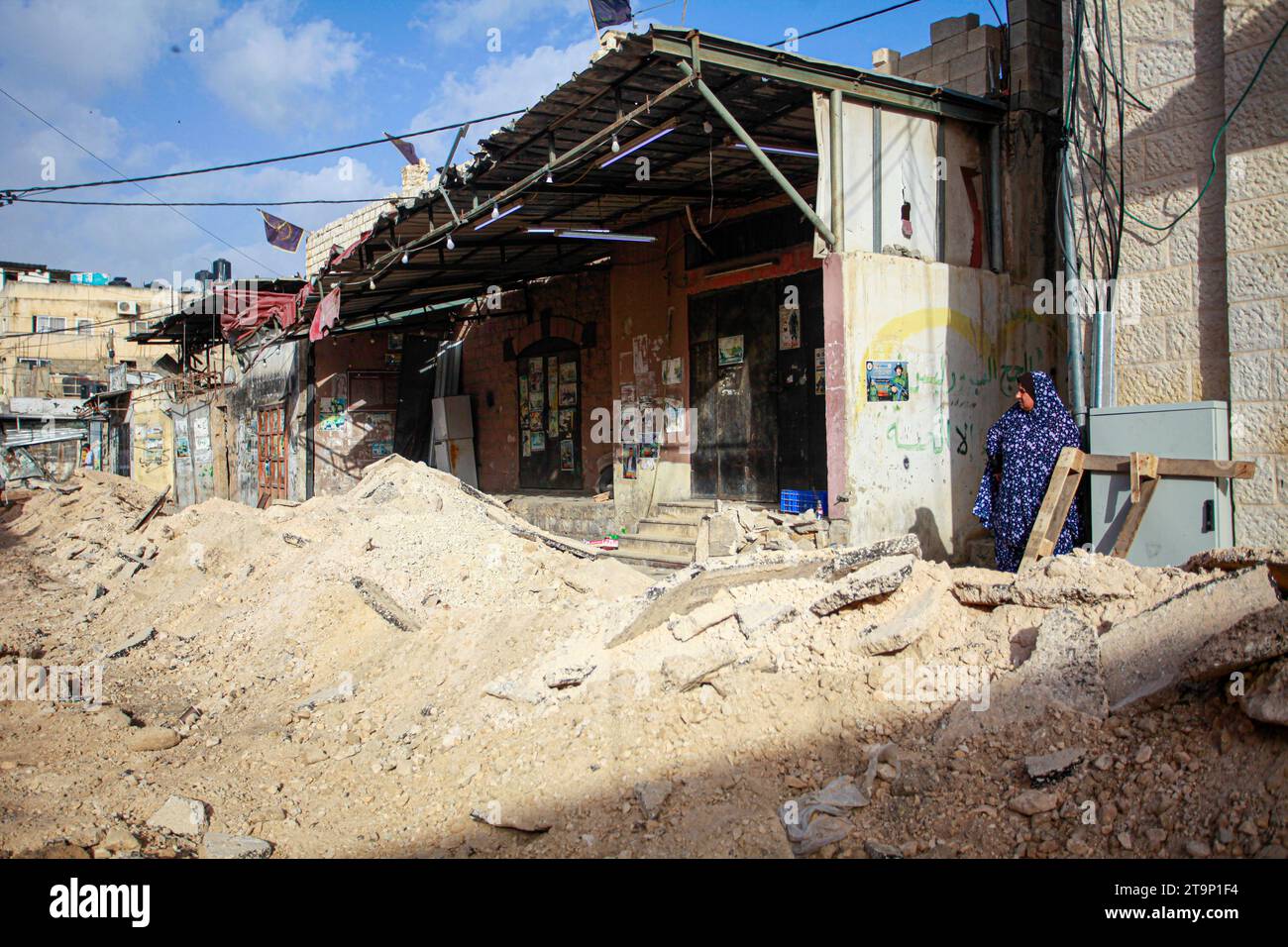 Jenin, Palestine. 26th Nov, 2023. A woman looks at a destroyed building ...