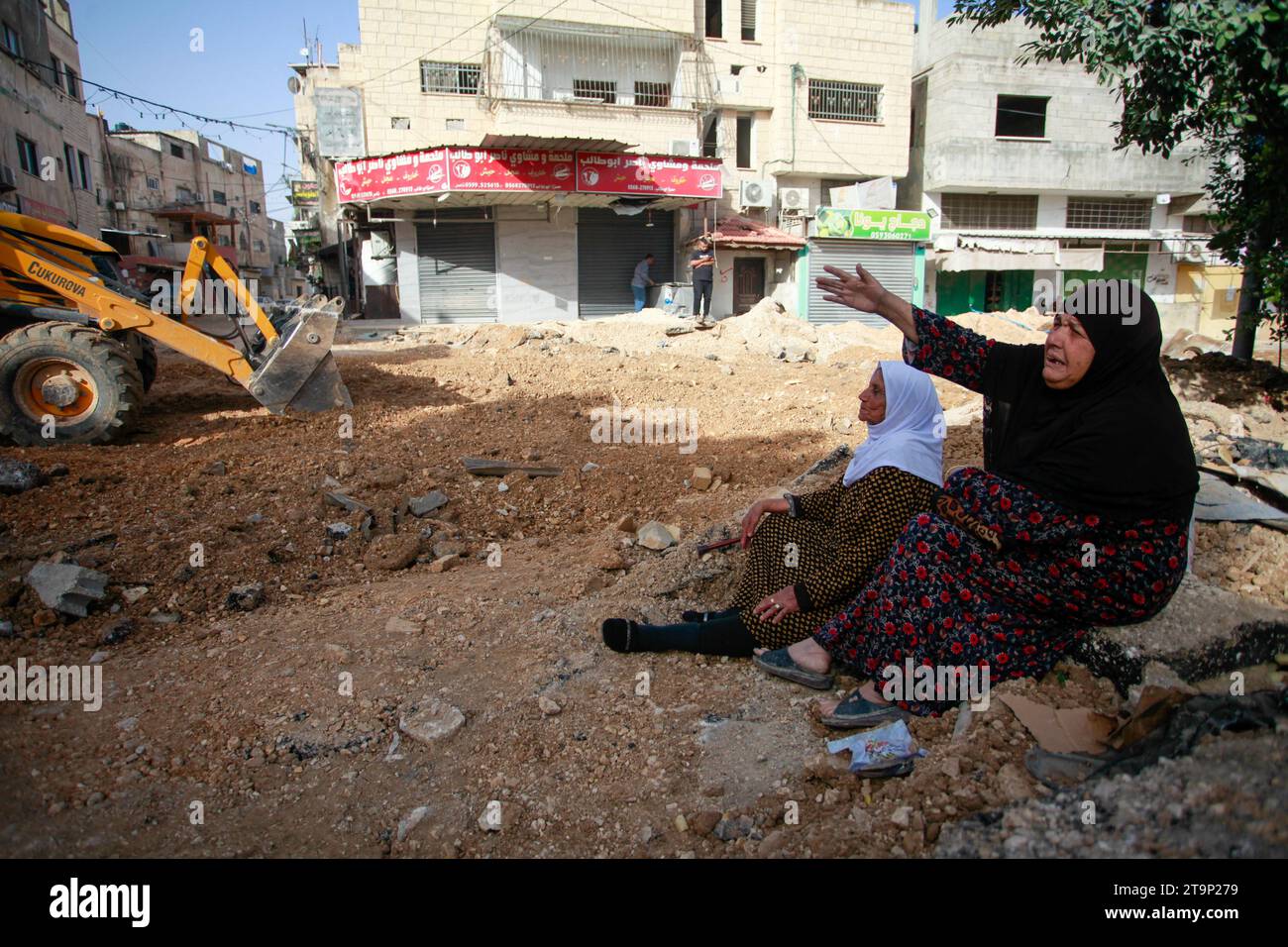 Jenin, Palestine. 26th Nov, 2023. Women sit nearby a destroyed building ...