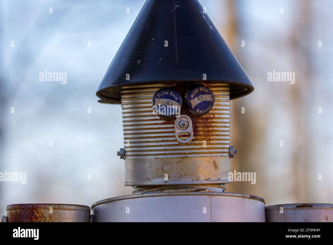 Hanging from branch lawn ornament made from used tin cans, with funnel ...