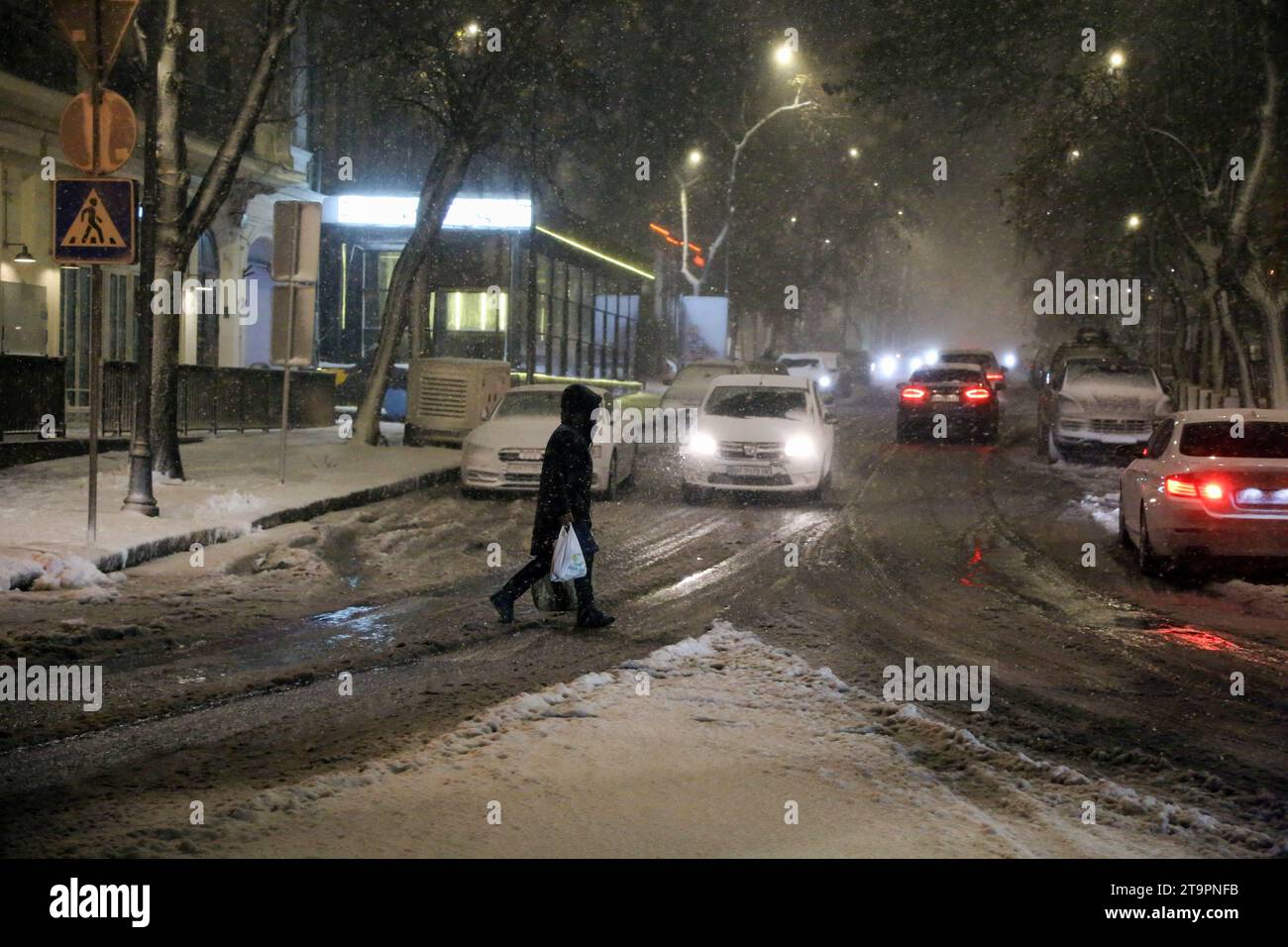 A woman crosses the road on Ekaterininskaya Street in a strong snowstorm. Odessa weather ...
