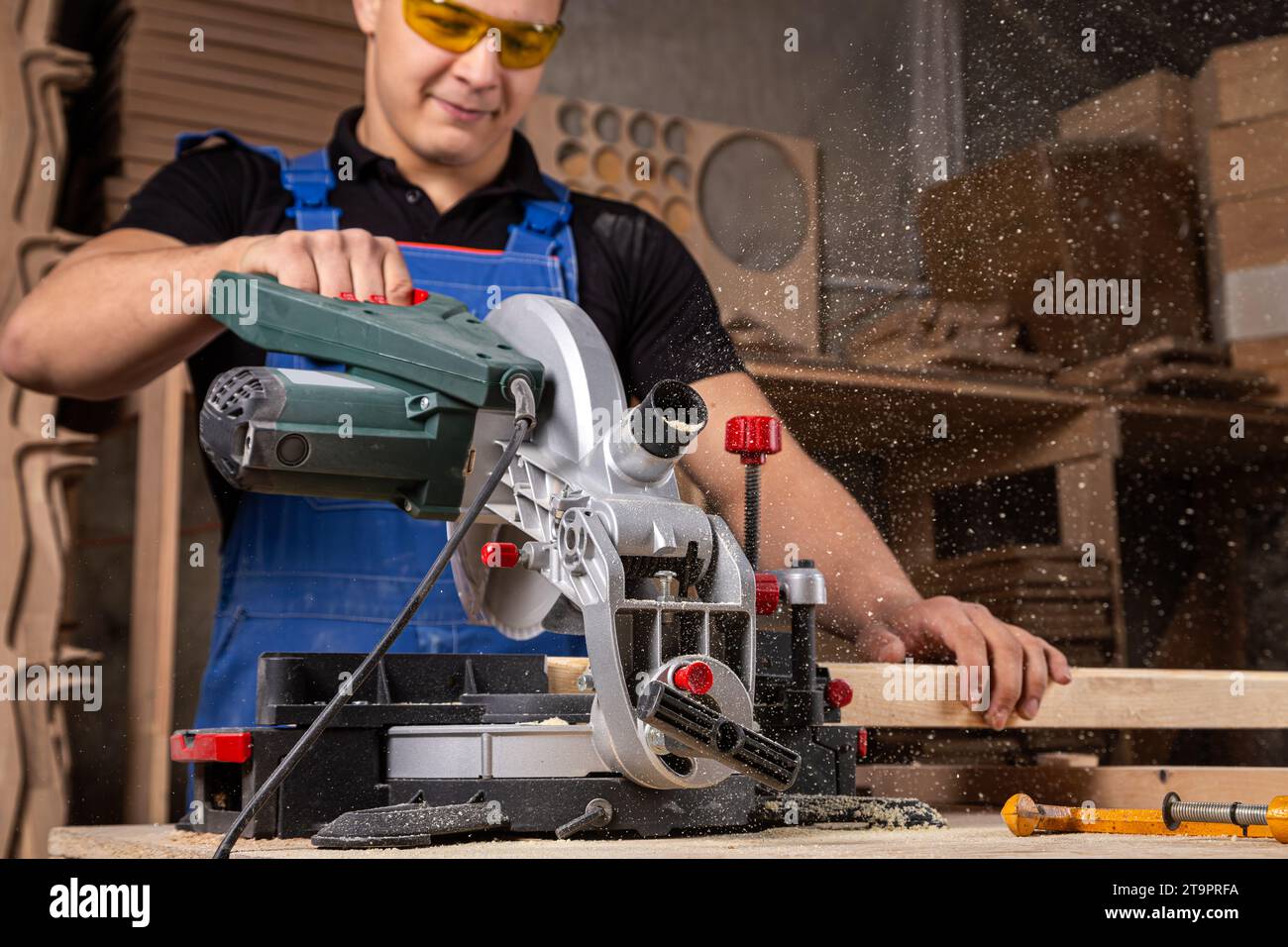 Carpenter cutting oriented strand board with circular saw in workshop ...