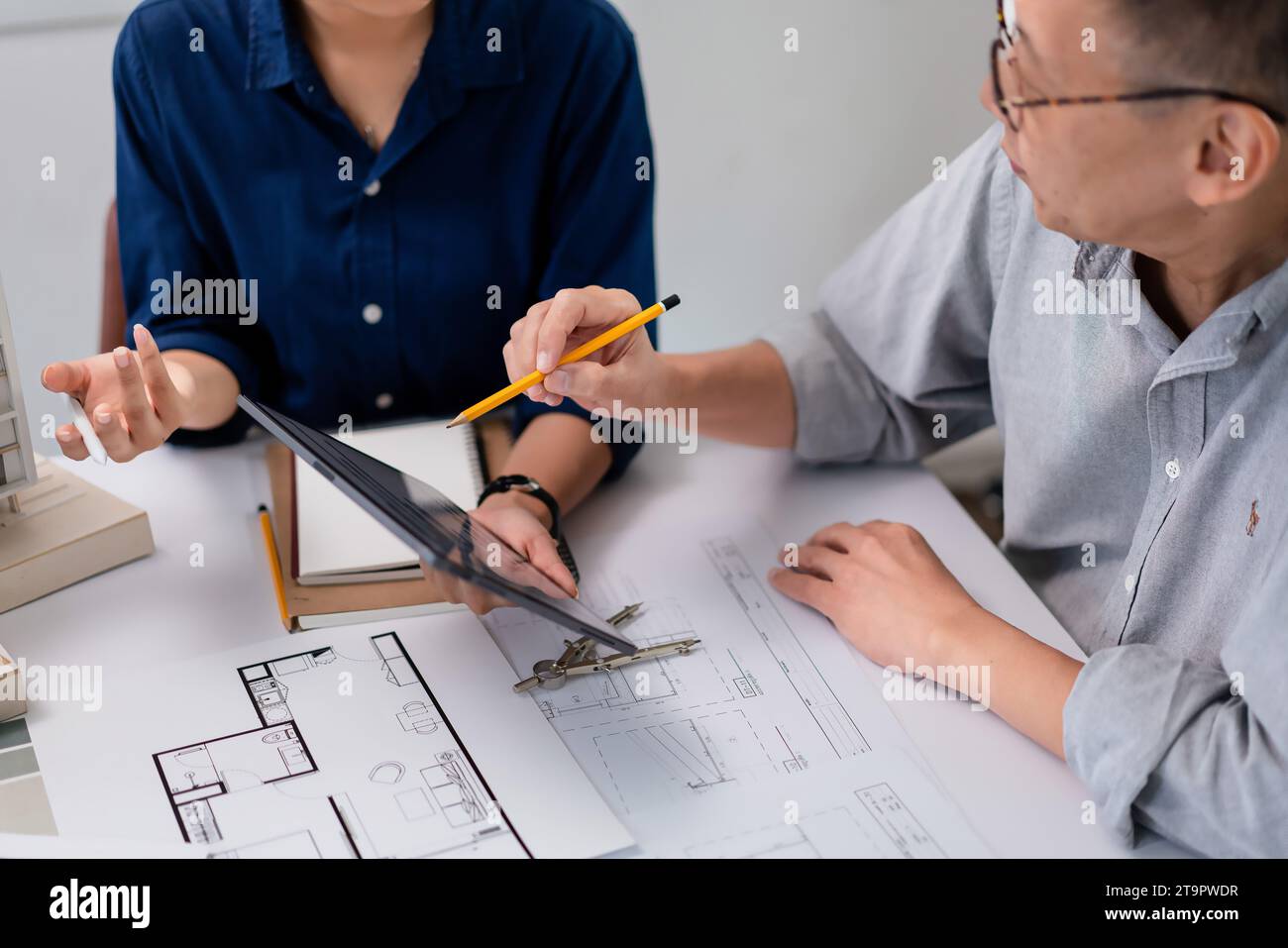 Two Architects Checking Blueprint On Tablet And Analyzing About Construction Of Building Project