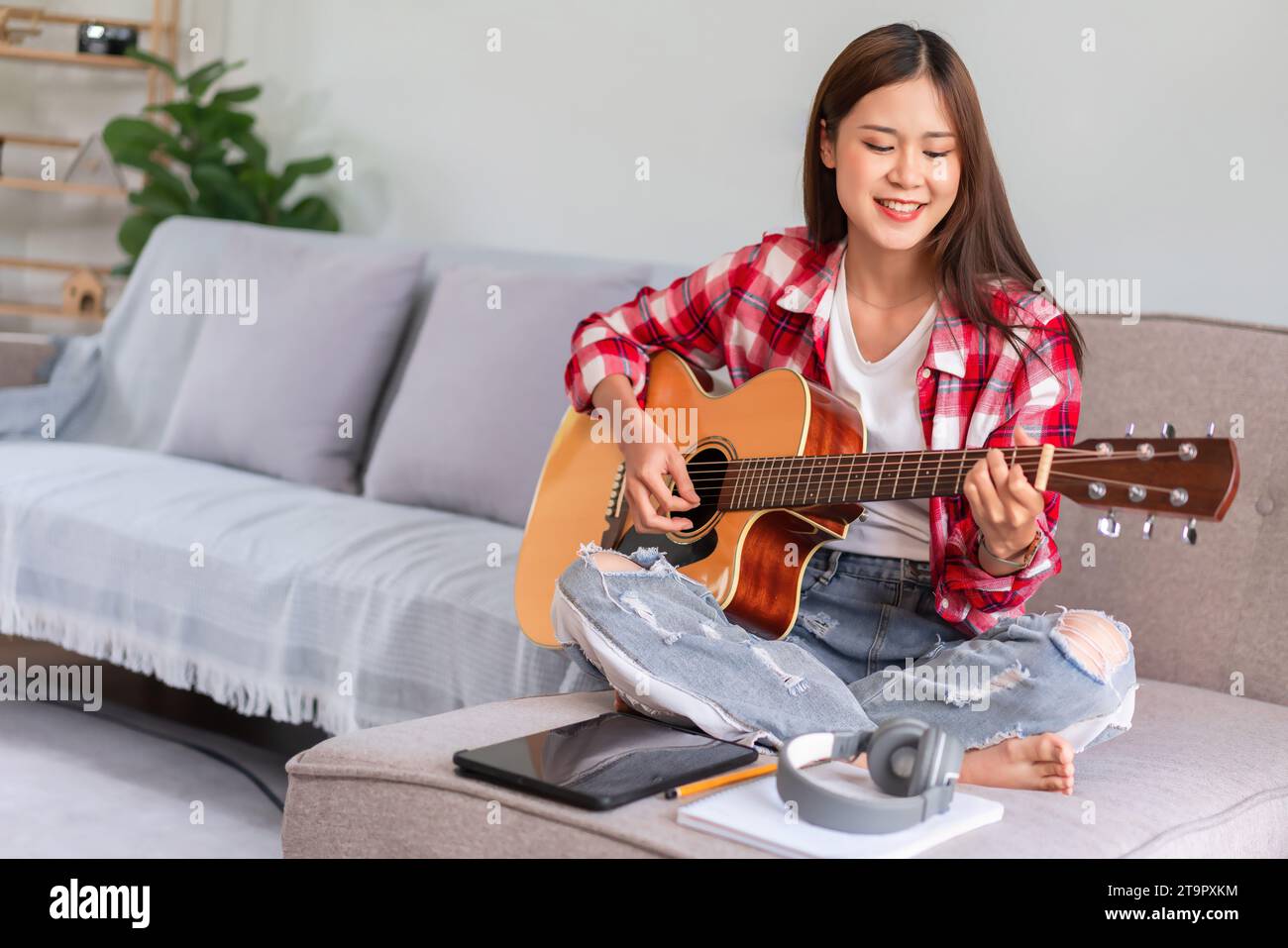 Hobby concept, Young woman sit on couch to singing and playing acoustic ...